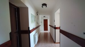 Um corredor com um radiador, um lustre no teto e uma porta no final.
