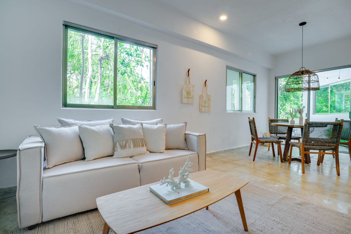Uma sala de estar moderna com sofá, mesa de centro e área de jantar.