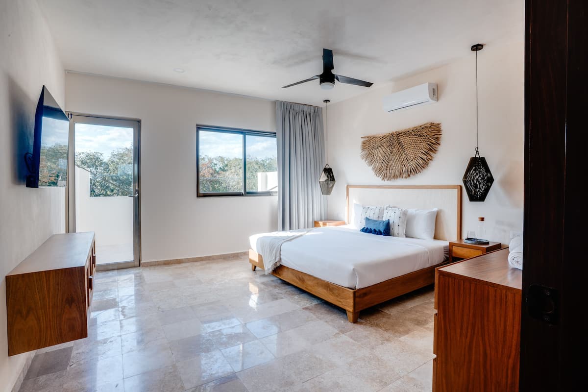 Quarto moderno com uma cama grande, uma escrivaninha e um ventilador de teto.