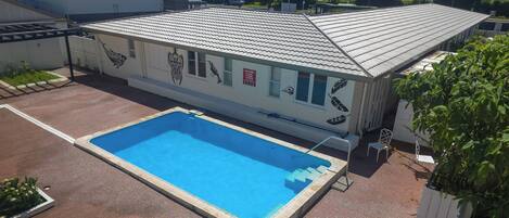 Um edifício com piscina, alpendre coberto e aviso com as regras da piscina.