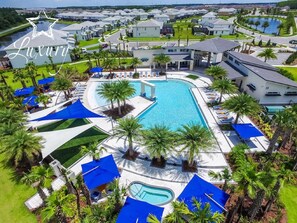 Um resort de luxo com uma grande piscina central, várias piscinas menores e um jardim bem cuidado com palmeiras e toldos azuis.