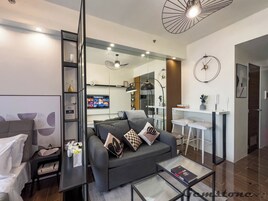 Uma sala de estar moderna com um sofá, mesa de centro e uma TV exibindo um filme.
