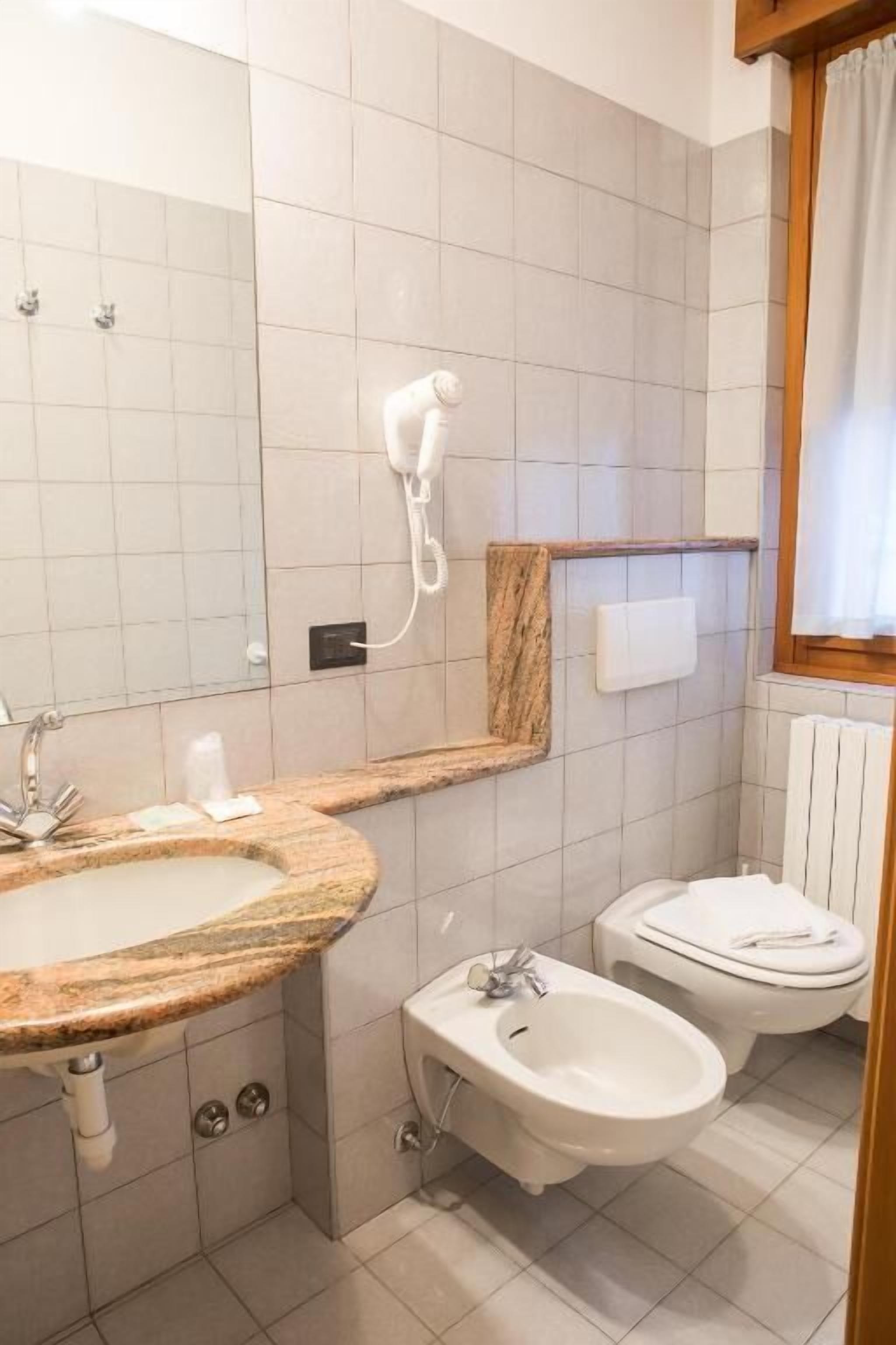Casa de banho com lavatório de mármore, bidé, sanita e um porta-toalhas.