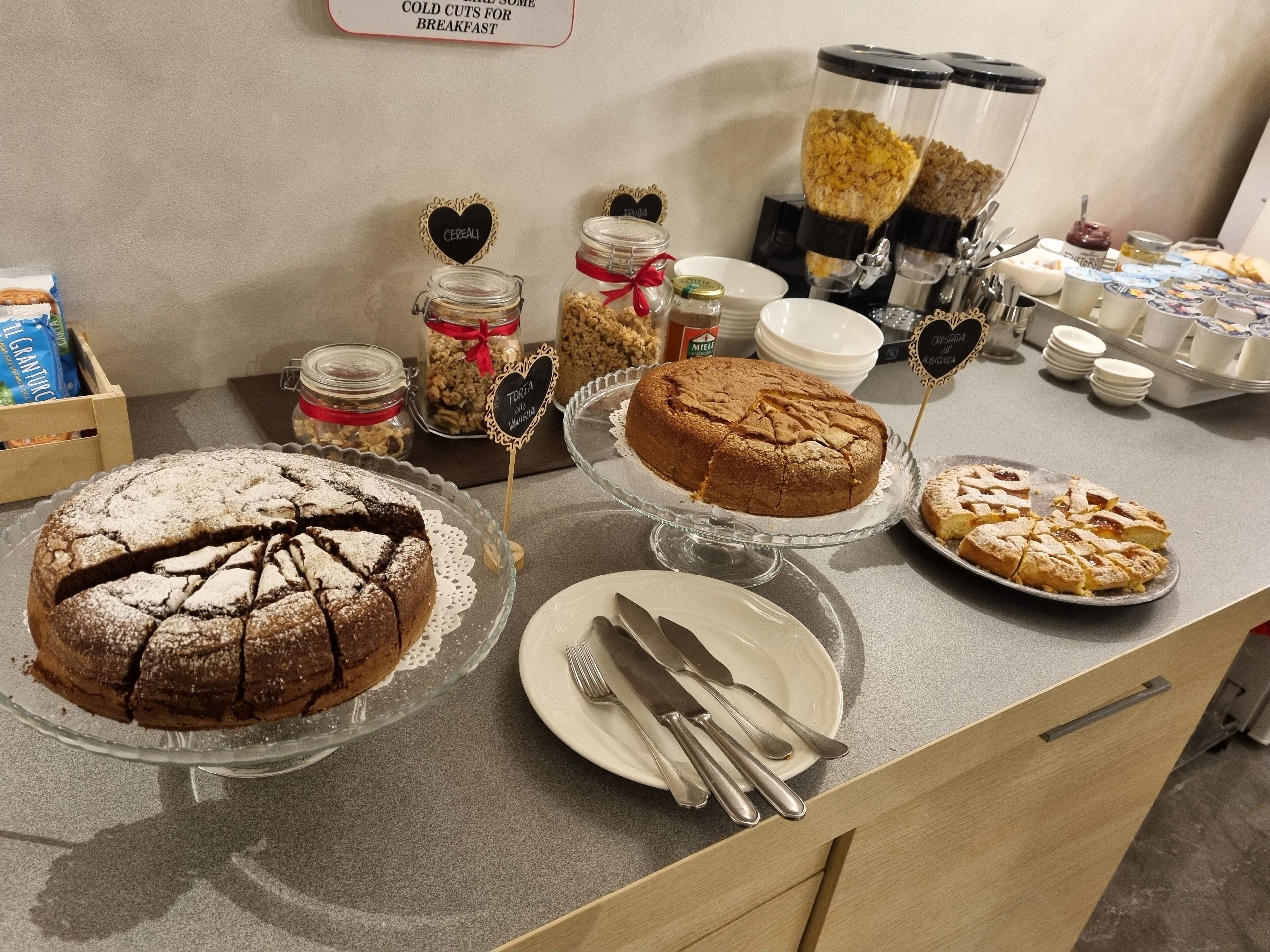 Um buffet de café da manhã com diversos alimentos e utensílios.