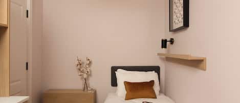 Quarto bem organizado com cama, mesa de cabeceira e prateleira na parede.