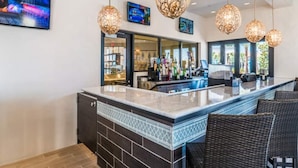 Uma área de bar com balcão, luminárias pendentes e cadeiras de vime.