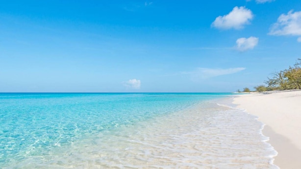 Uma praia com águas turquesa cristalinas e areia branca.