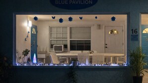 Quarto de hotel com janela, porta e uma placa indicando 'BLUE PAVILION', com o número '16' na parede.