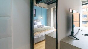 Quarto moderno com cama, luminária pendente e vista para o exterior.