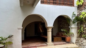 Um pátio com piscina, arcos e plantas em vasos.