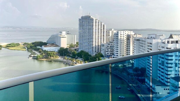 Um edifício alto com vista para um corpo d'água e outros edifícios ao fundo.