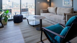 Uma sala de estar moderna com uma janela grande, um sofá, uma mesa de centro e uma poltrona.