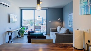 Uma sala de estar moderna com piso de madeira, um sofá, uma mesa de centro e uma luminária pendente.