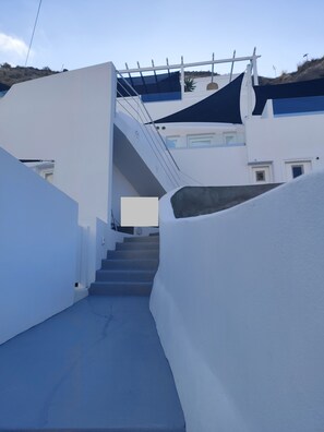 Um edifício branco com uma escadaria que leva a um segundo andar.