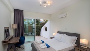 Quarto com cama, mesas de cabeceira, escrivaninha e uma cadeira.