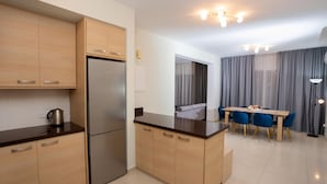 Cozinha moderna com armários de madeira, uma geladeira de aço inoxidável e um espaço de jantar com mesa e cadeiras.