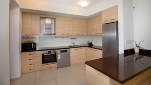 Uma cozinha moderna com armários de madeira, eletrodomésticos de aço inoxidável e bancada escura.