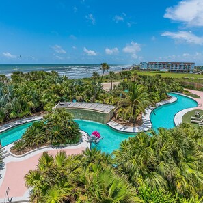 Um resort com uma grande área de piscina, palmeiras e vista para o oceano.