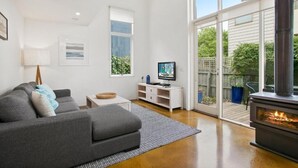Uma sala de estar moderna com um sofá cinza, um móvel branco para entretenimento e uma lareira.