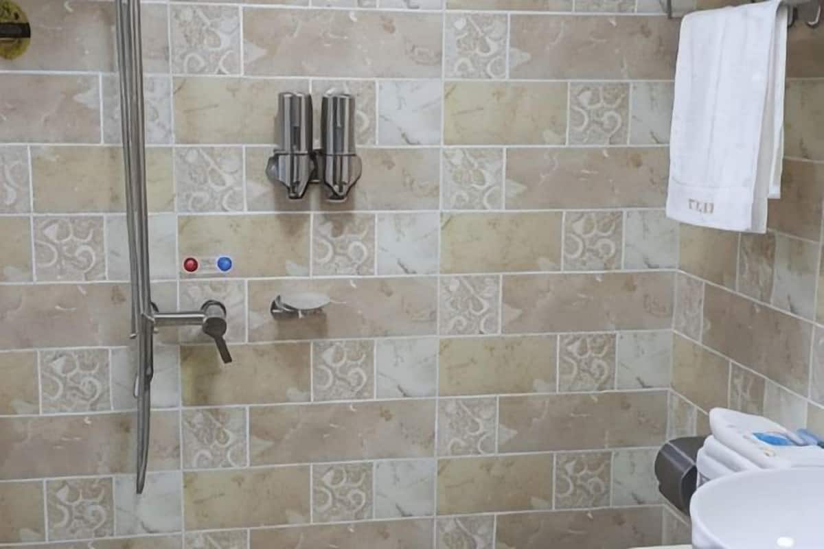 Um chuveiro com porta de vidro, porta-toalhas e secador de mãos.