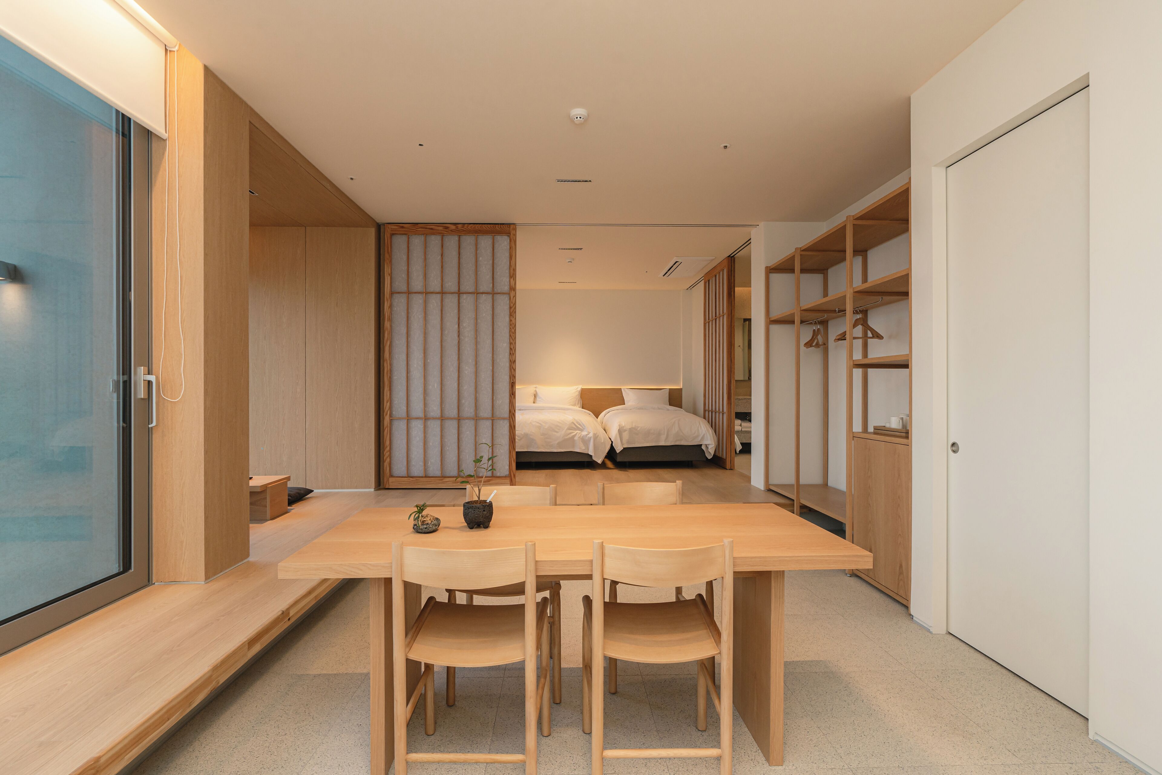 Quarto moderno e minimalista com uma cama grande, móveis de madeira e um painel deslizante shoji.
