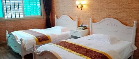 Quarto de hotel com duas camas brancas, parede de tijolos, janela com persianas e mesa de cabeceira com abajur.