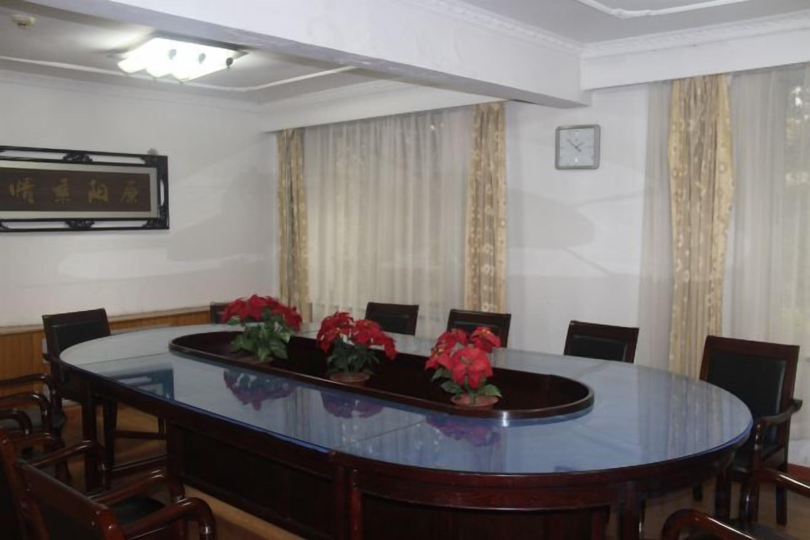 Uma sala de conferências com uma grande mesa oval, cadeiras e um relógio na parede.