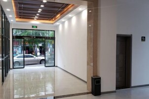 Um hall de hotel com entrada de vidro, uma lixeira e uma porta com o número 1.