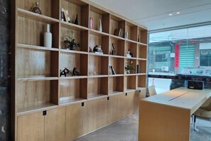 Uma área de recepção com um balcão de madeira e uma grande estante com diversos objetos.