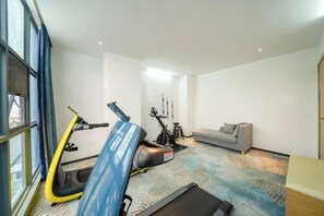 Uma sala de estar moderna com esteira ergométrica, bicicleta ergométrica e sofá.