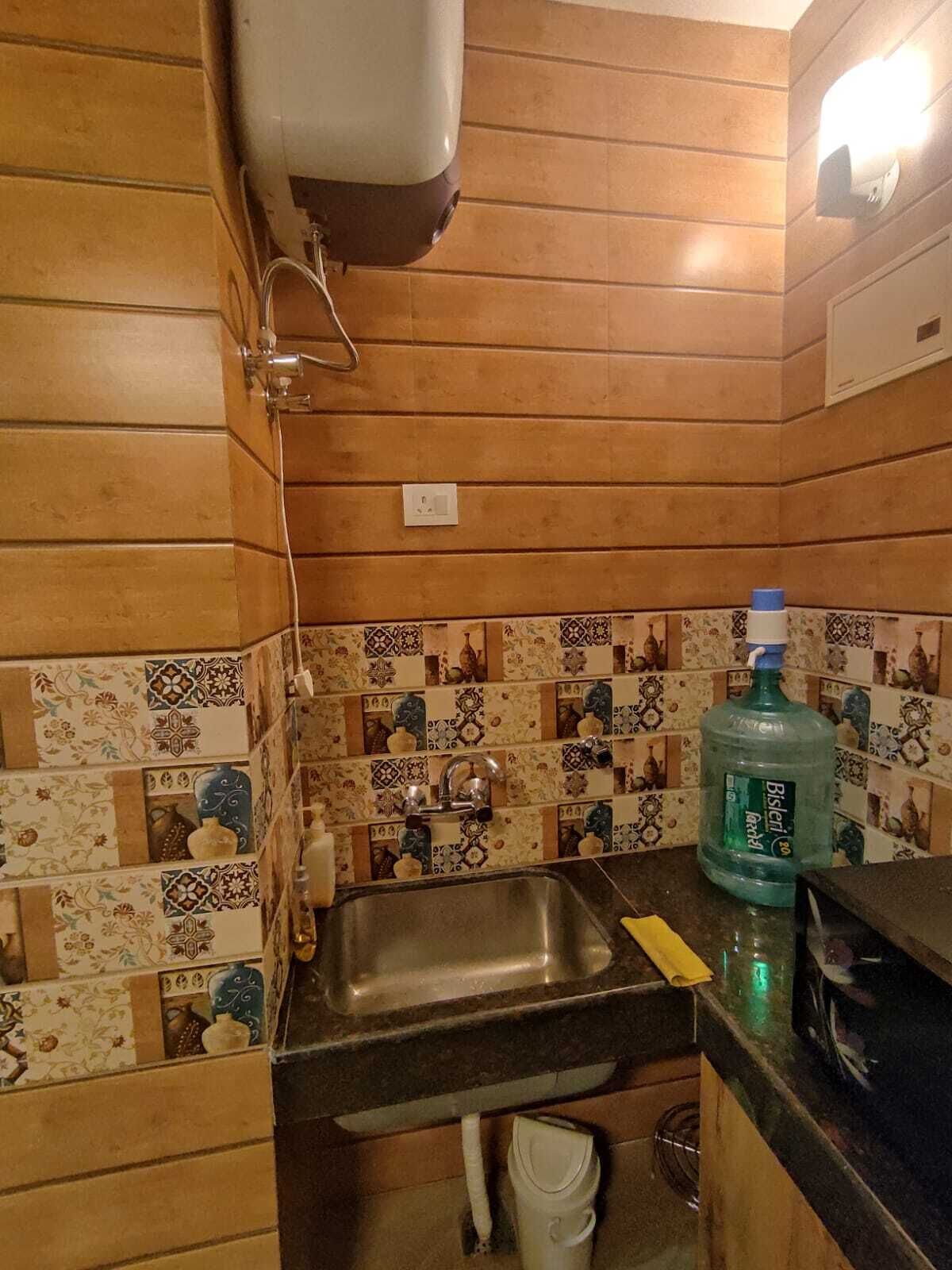 Uma cozinha compacta com pia, dispenser de água e painel de azulejos.