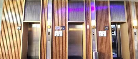 Área de elevadores com três elevadores, cada um identificado com as placas P1, P2 e P3.