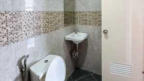 Casa de banho com sanita, lavatório e chuveiro.