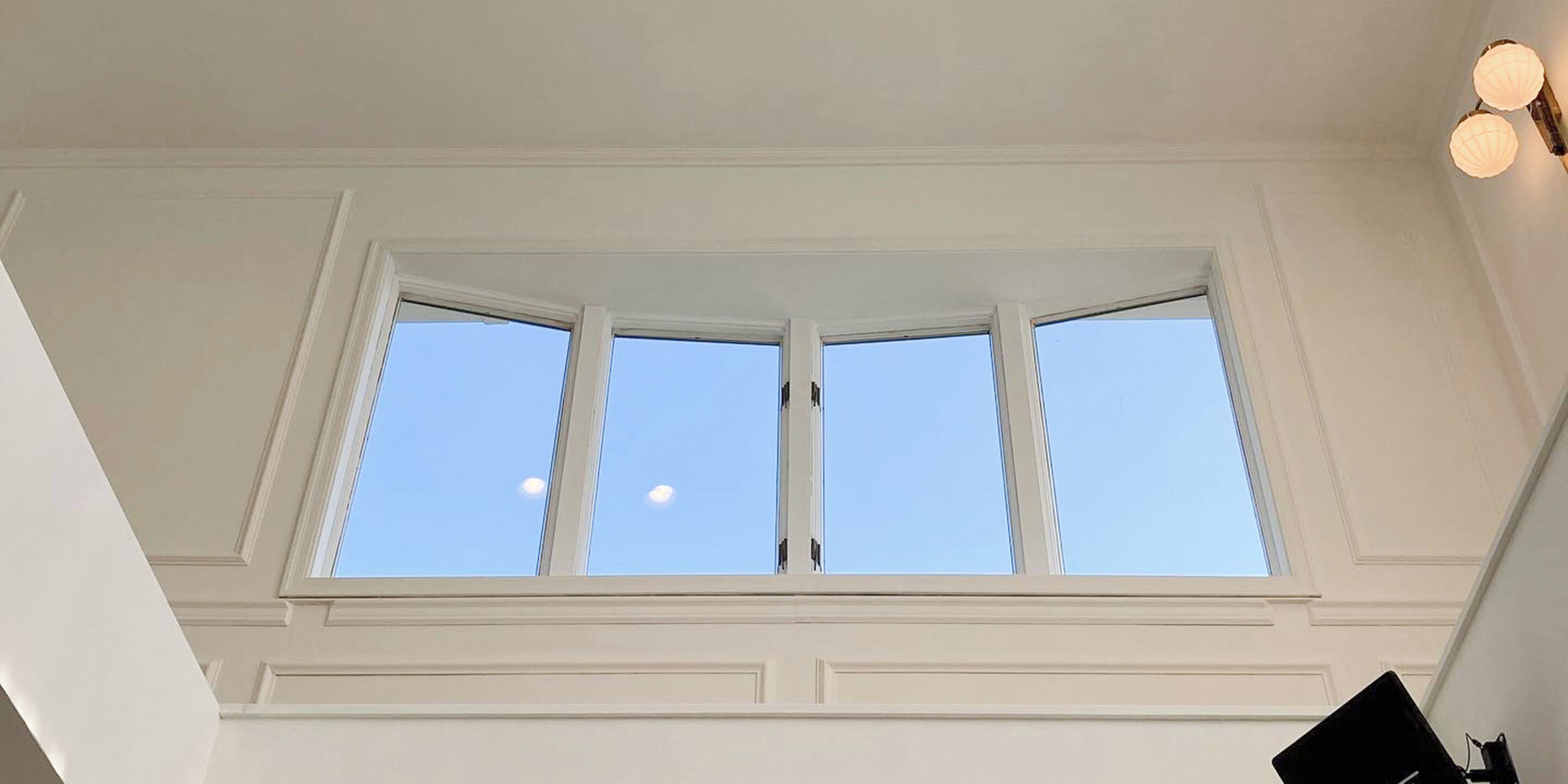 Um quarto com um amplo parapeito, paredes brancas e teto de design simples.