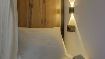Uma cama beliche com cabeceira de madeira, uma mesa de cabeceira com abajur e um livro aberto na cama.