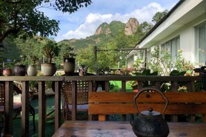 Um deck de madeira com vasos de plantas, um banco e vista para uma montanha.