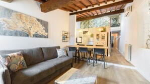 Uma sala de estar moderna com um sofá cinzento, uma mesa de centro e uma área de cozinha com banquetas.