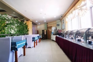 Disposição de buffet com estações de comida cobertas, um balcão longo e uma área de estar com mesas e cadeiras.