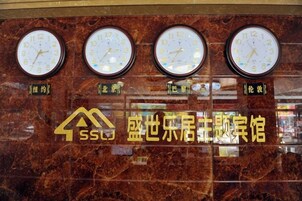 Quatro relógios de parede com texto em chinês e um logotipo numa parede de mármore.