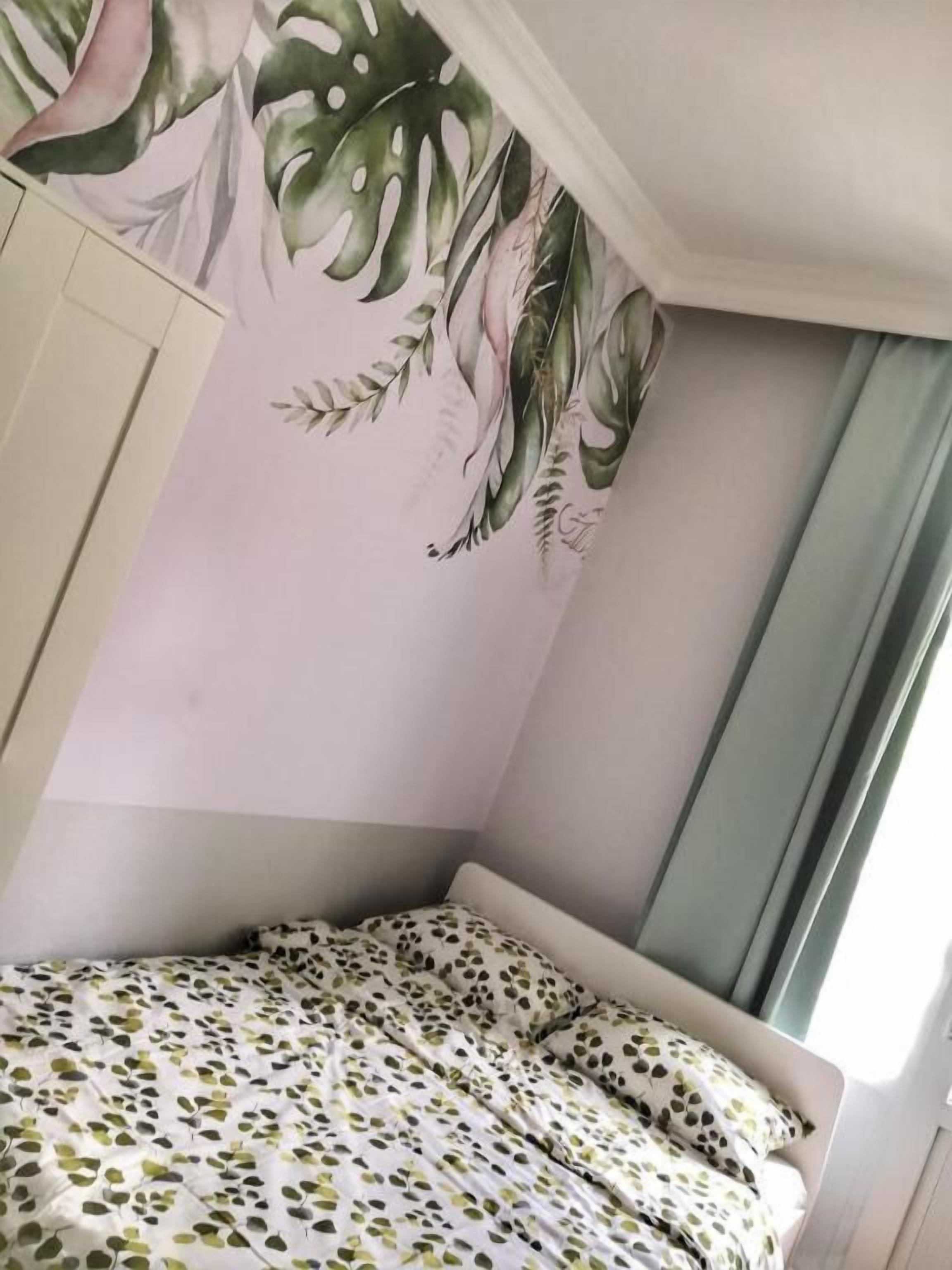 Quarto com cama, painel decorativo na parede e janela.