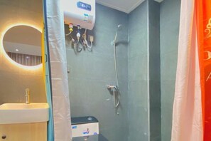 Casa de banho com design moderno, apresentando uma pia, chuveiro com duche manual e um porta-toalhas.