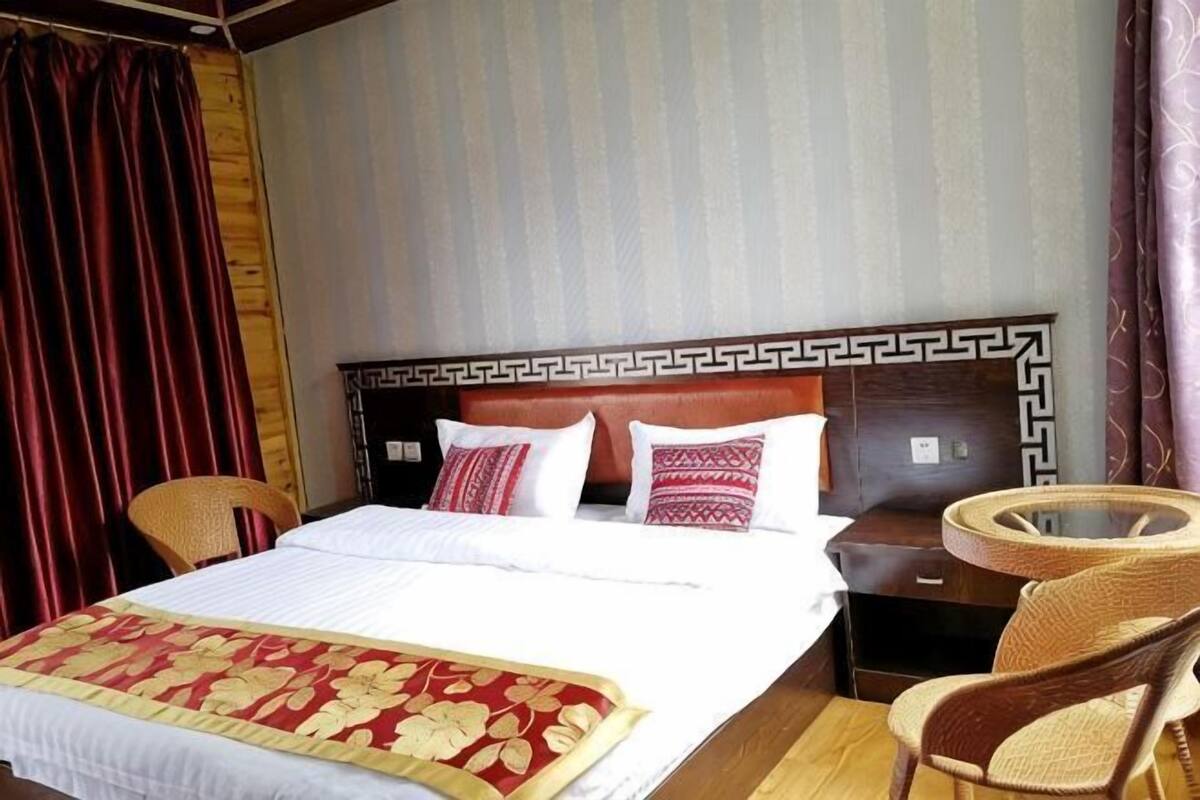 Quarto de hotel com uma cama, uma mesa redonda de vime e uma cadeira.