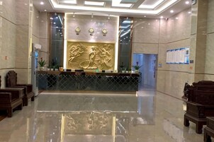 Área de recepção de hotel com piso de mármore polido, balcão de atendimento com detalhe decorativo e disposição de assentos em ambos os lados.