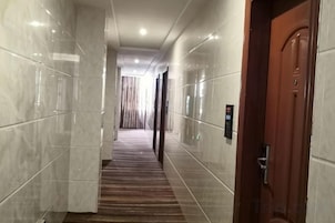 Um corredor com piso de madeira, paredes brancas e uma porta à direita.