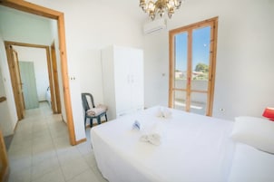 Quarto de hotel com cama, guarda-roupa, cadeira e vista pela janela.