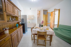 Uma cozinha com armários de madeira, uma mesa de jantar com cadeiras, uma geladeira e um sofá verde.