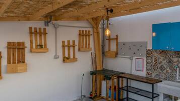 Cozinha rústica com vigas de madeira, mesa de madeira e luminária pendente.