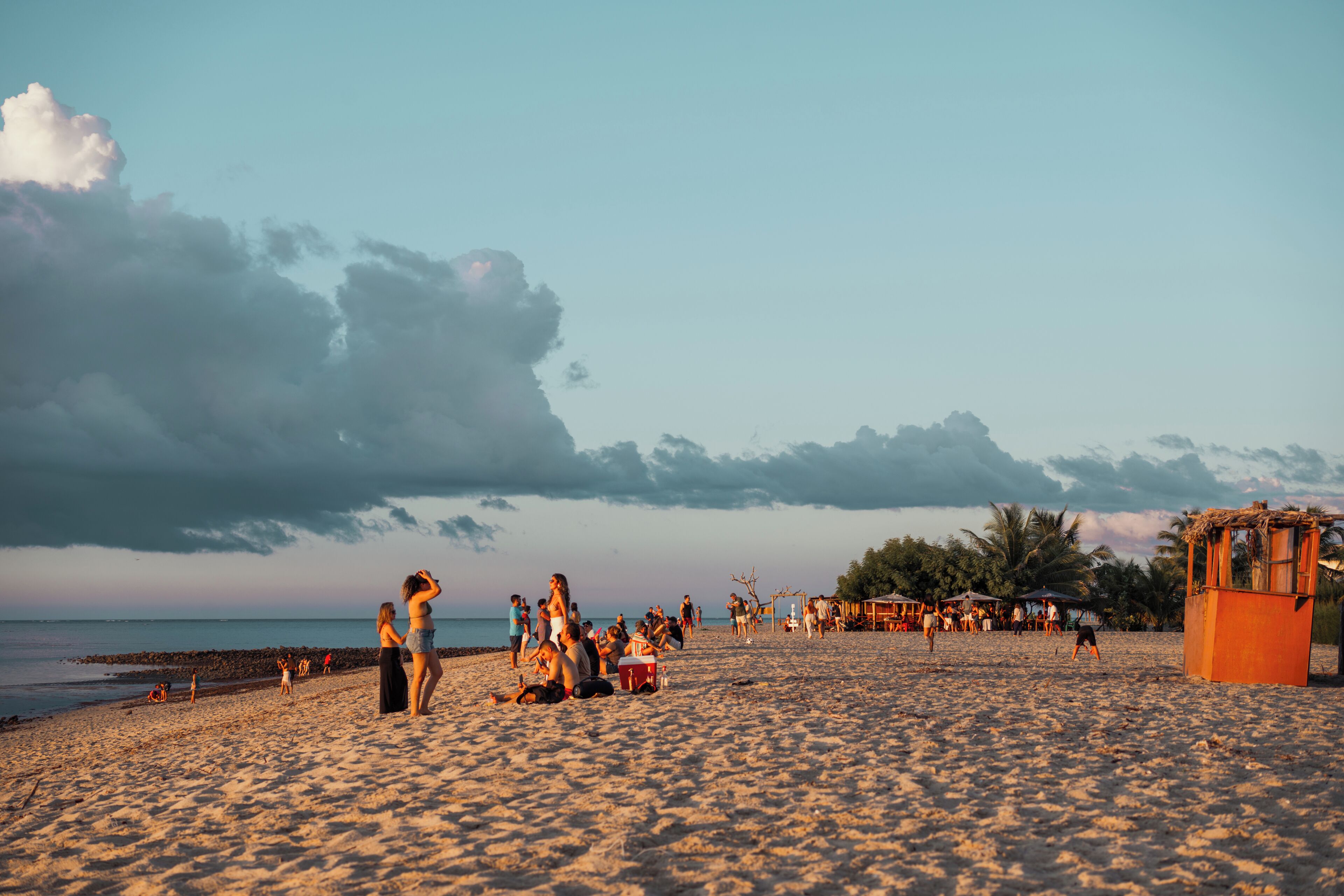 Uma praia com pessoas relaxando e uma torre de salva-vidas.