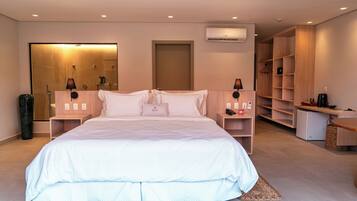 Quarto de hotel moderno com uma cama grande, mesas de cabeceira, um guarda-roupa e um banheiro com chuveiro.