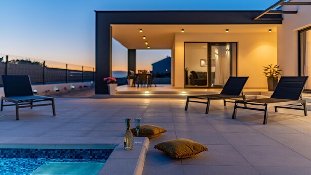 Um pátio moderno ao ar livre com piscina, espreguiçadeiras e área de refeições.